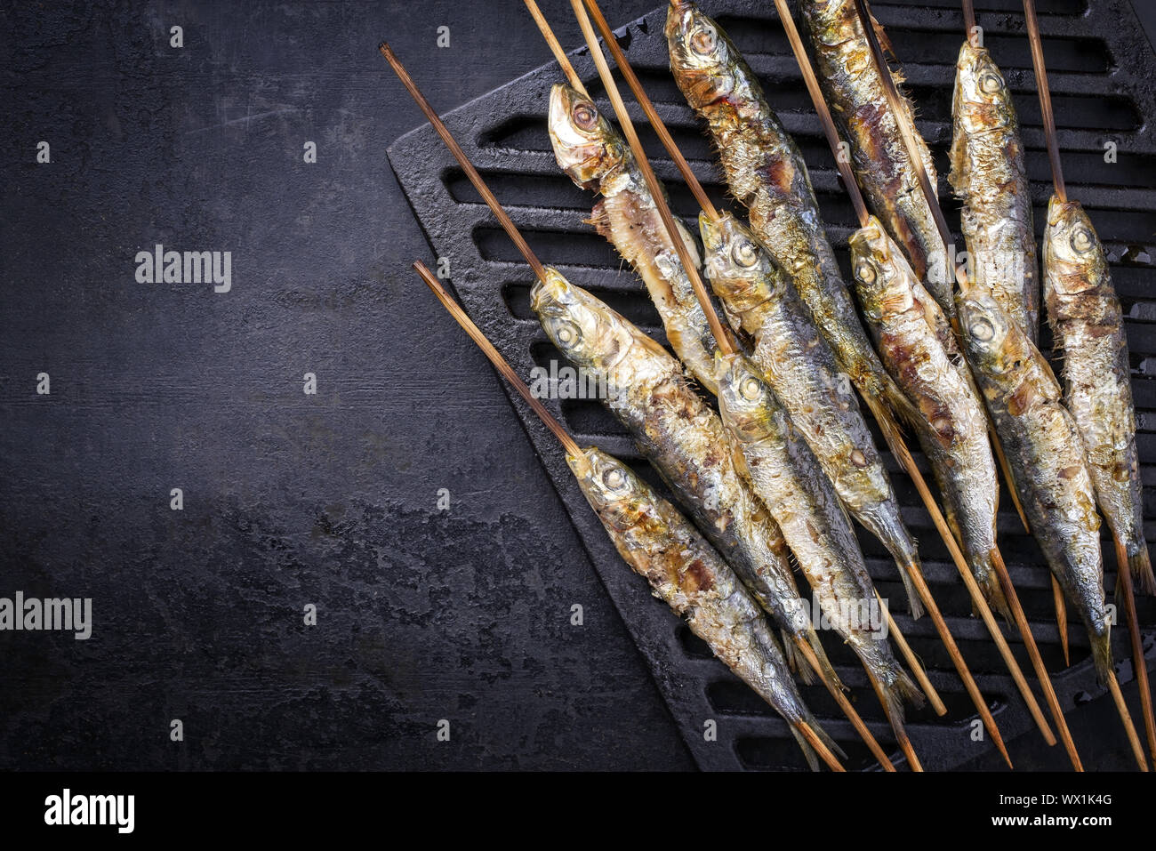 Traditional Spanish barbecue sardines on a wooden skewer as top view on ...