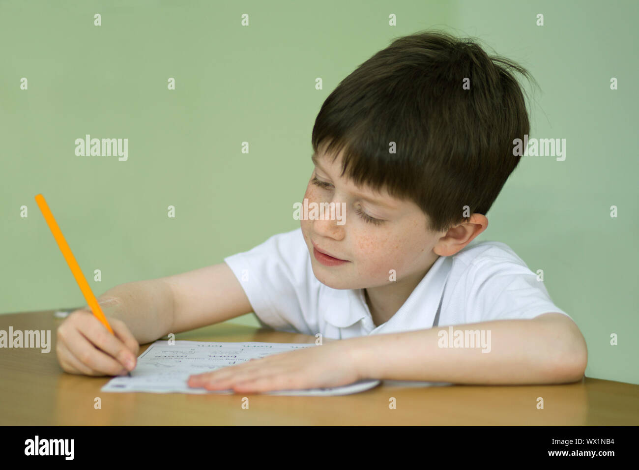 Young boy at a table doing school work Stock Photo - Alamy