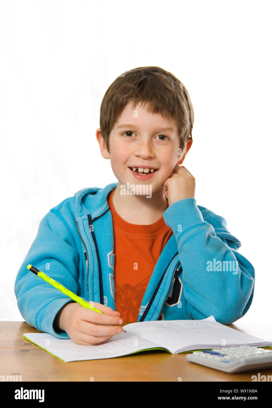 Happy young boy smiling whilst doing homework Stock Photo - Alamy