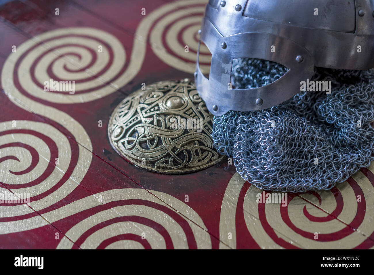 viking helmet with chain mail on a red shield with golden shapes of sun ...