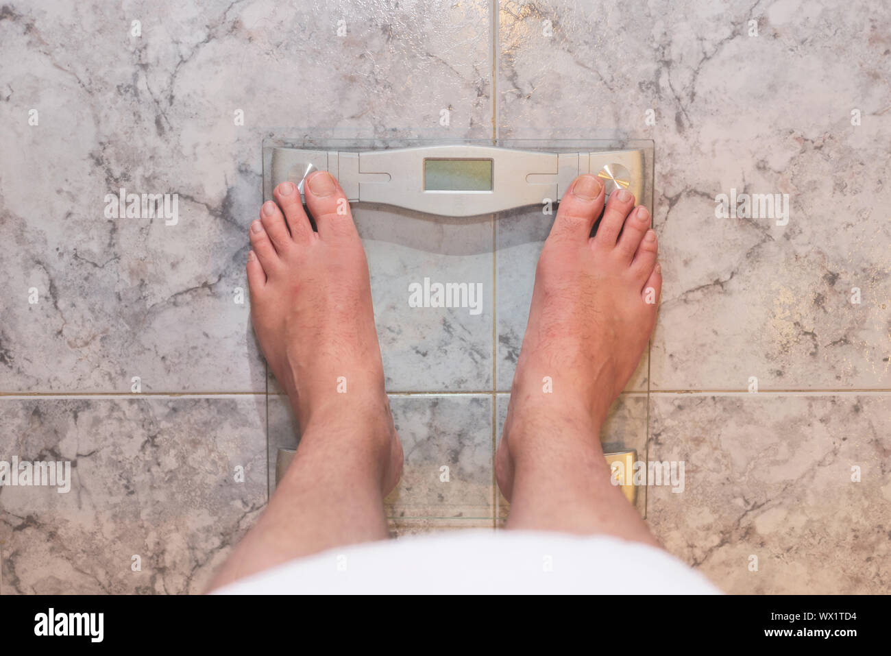 Man feet standing on weight scale Stock Photo - Alamy