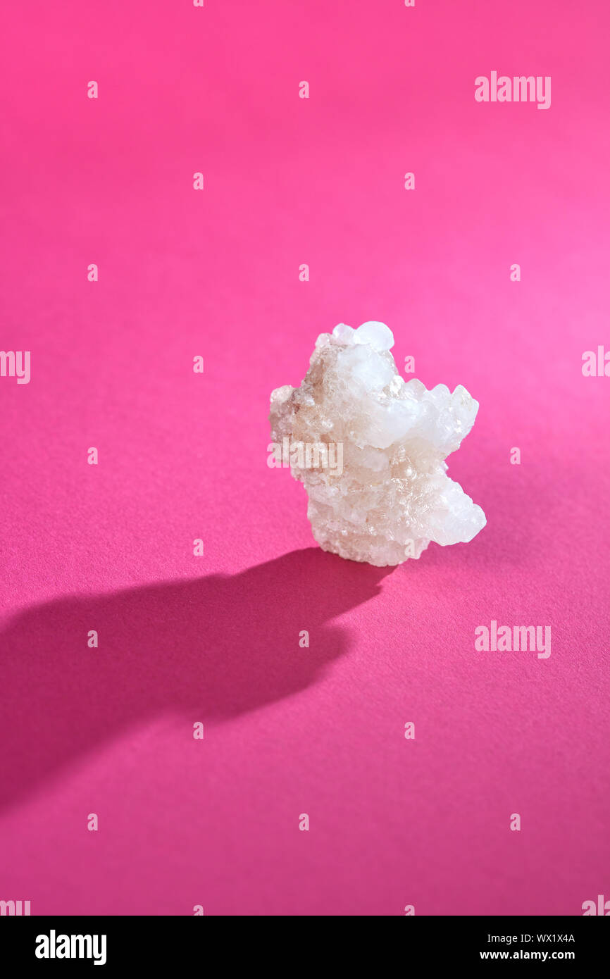 Large stone sugar in a piece on a pink background with long shadows ...