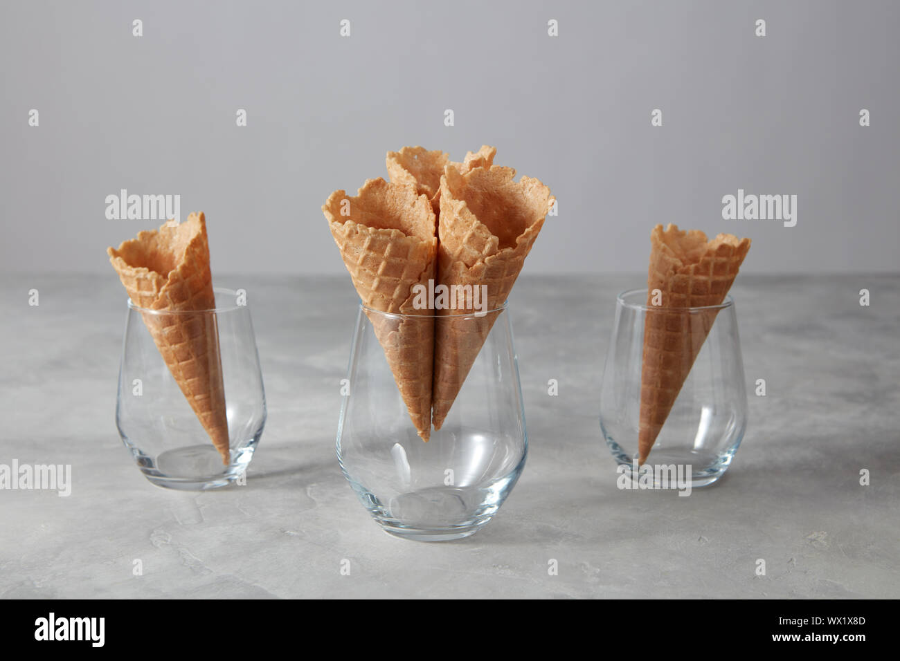 Sweet wafer cones for dessert empty in a glasses on a light gray ...