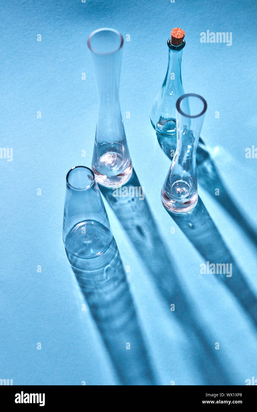 Glass vases empty with shadows and reflection on the surface on a blue ...