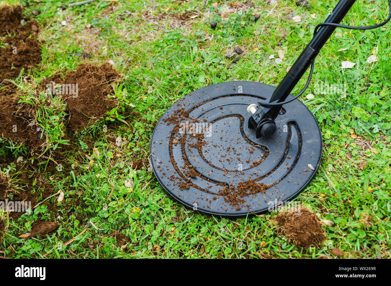 Metal detector searching for treasure in the ground Stock Photo - Alamy