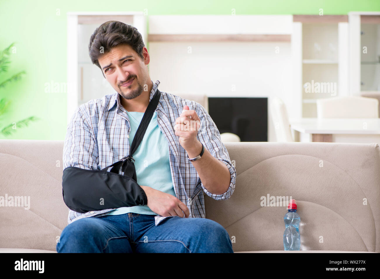 The young student man with hand injury sitting on the sofa Stock Photo ...