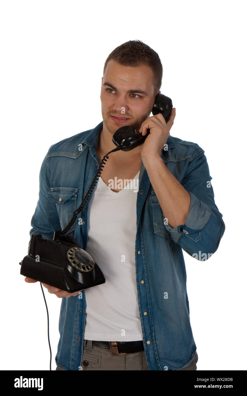 Young man making a phone call with an old telephone against a white ...