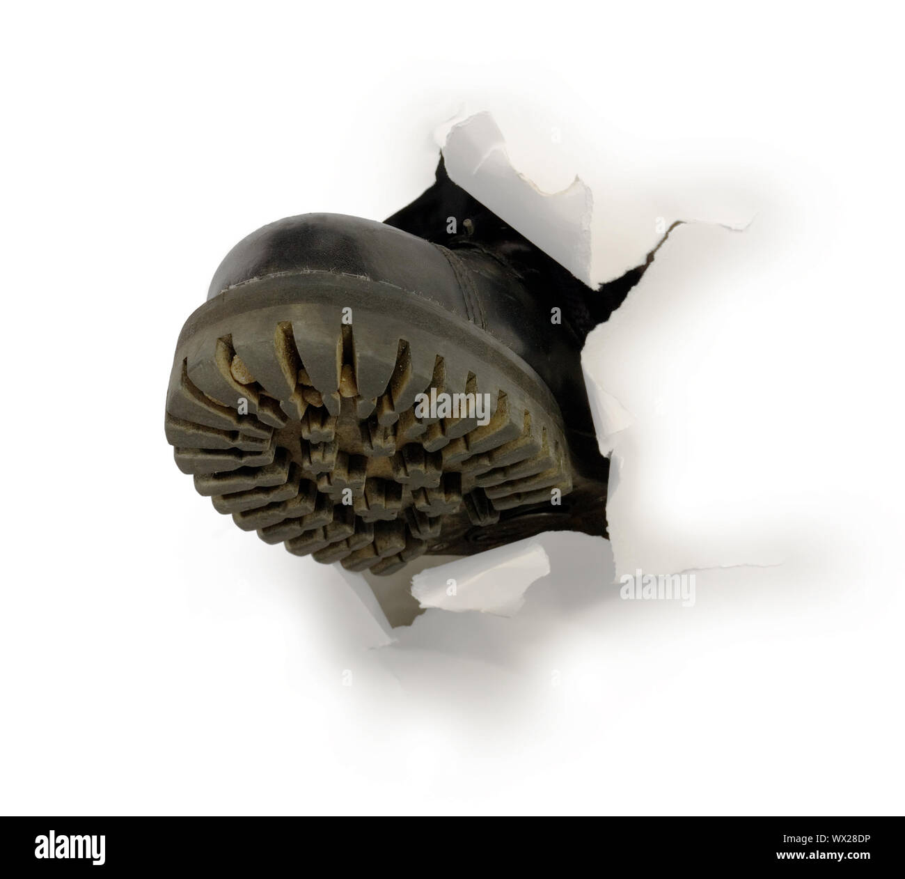 Male black boot in hole of paper photographed on a white background ...