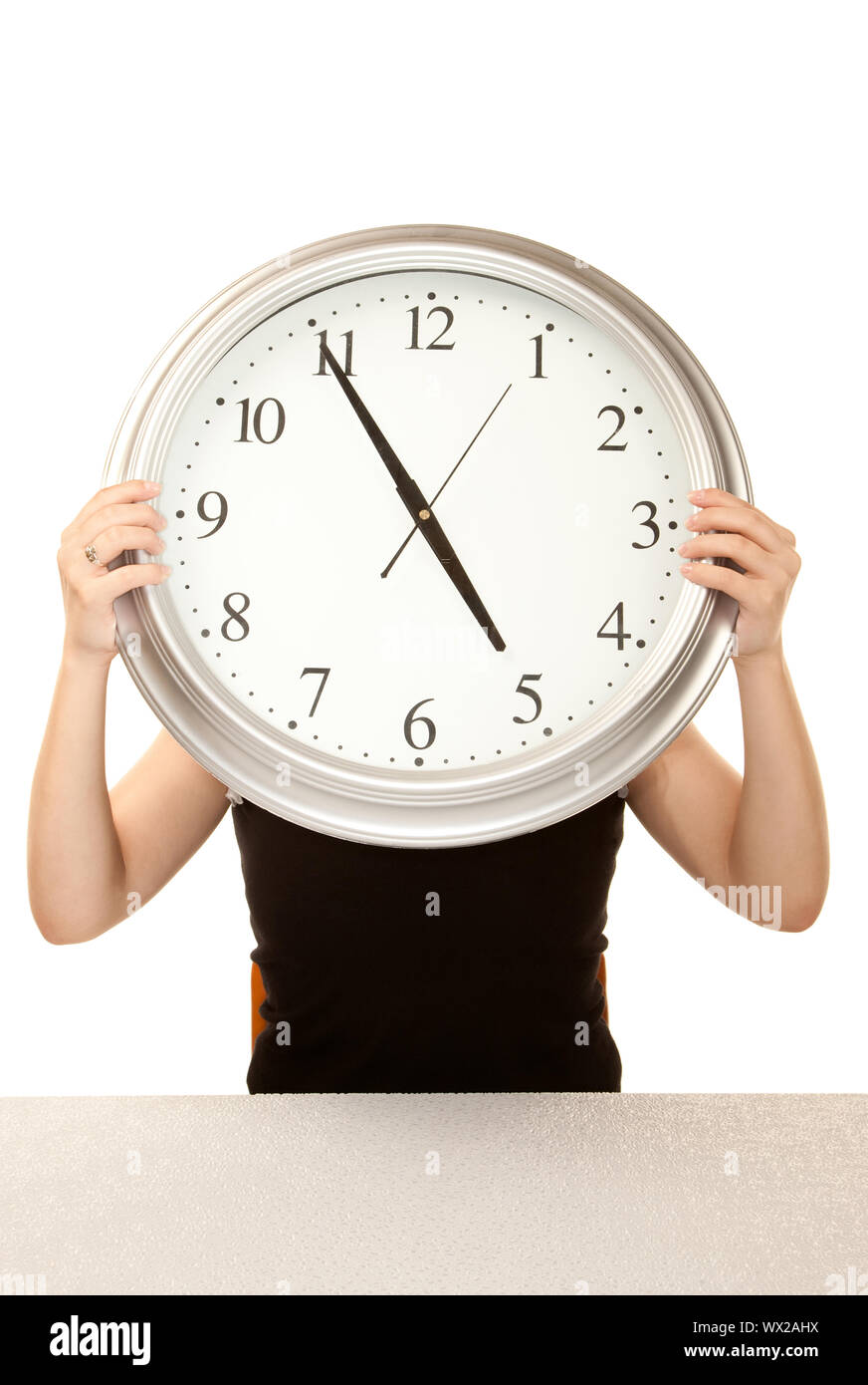 Woman at work holding up large office clock Stock Photo - Alamy