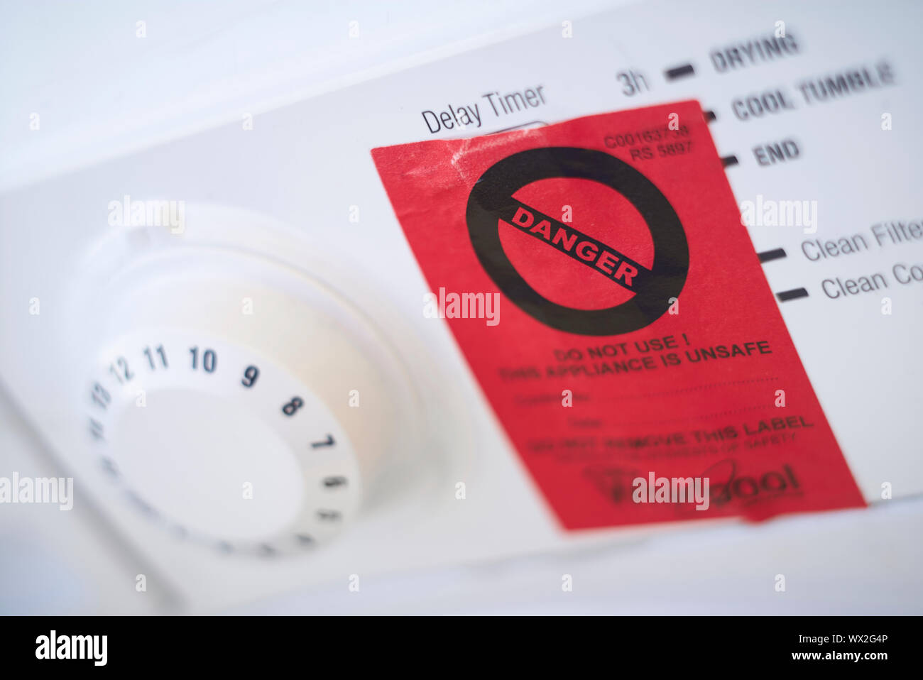 Red danger sign stuck on the front of a white Hotpoint Whirlpool tumble ...