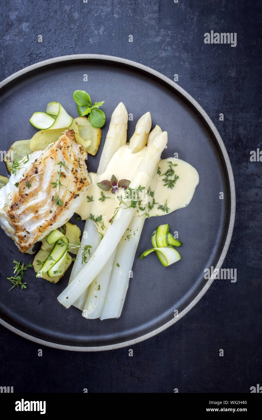 Modern German fried cod fish filet with white asparagus in hollandaise ...