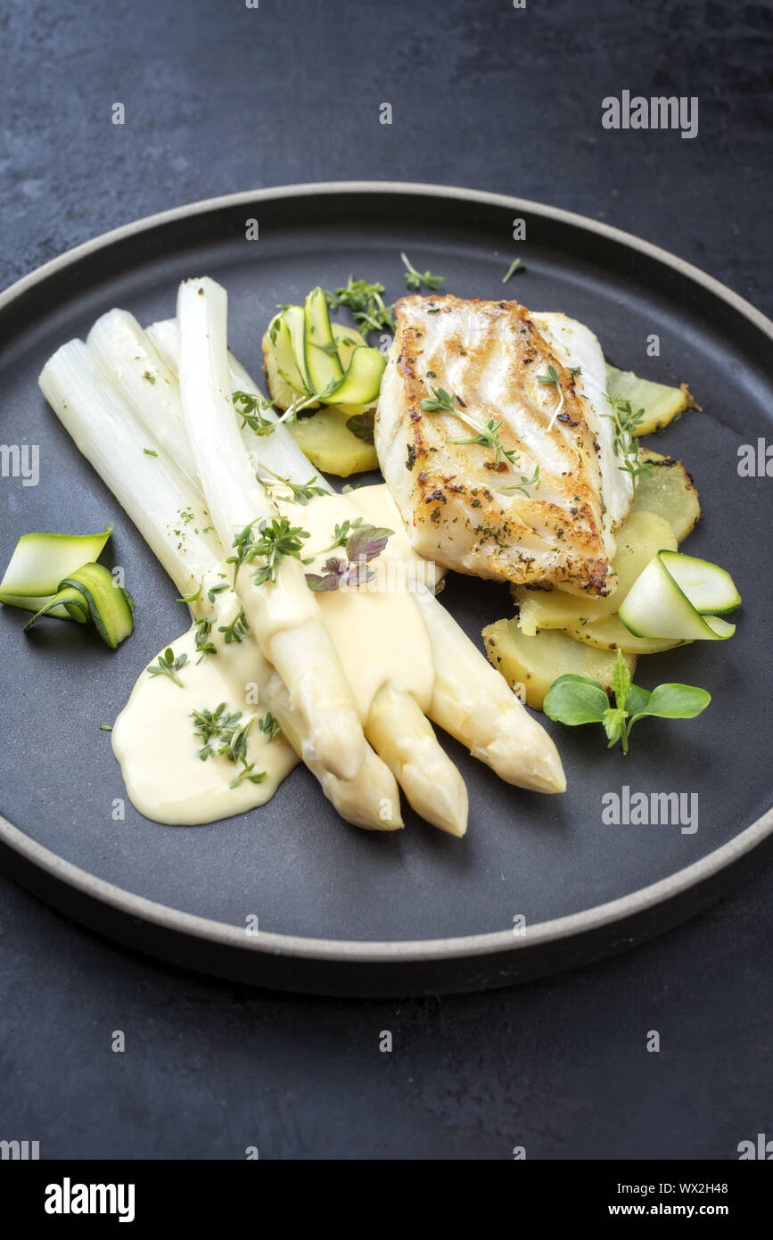 Modern German fried cod fish filet with white asparagus in hollandaise ...