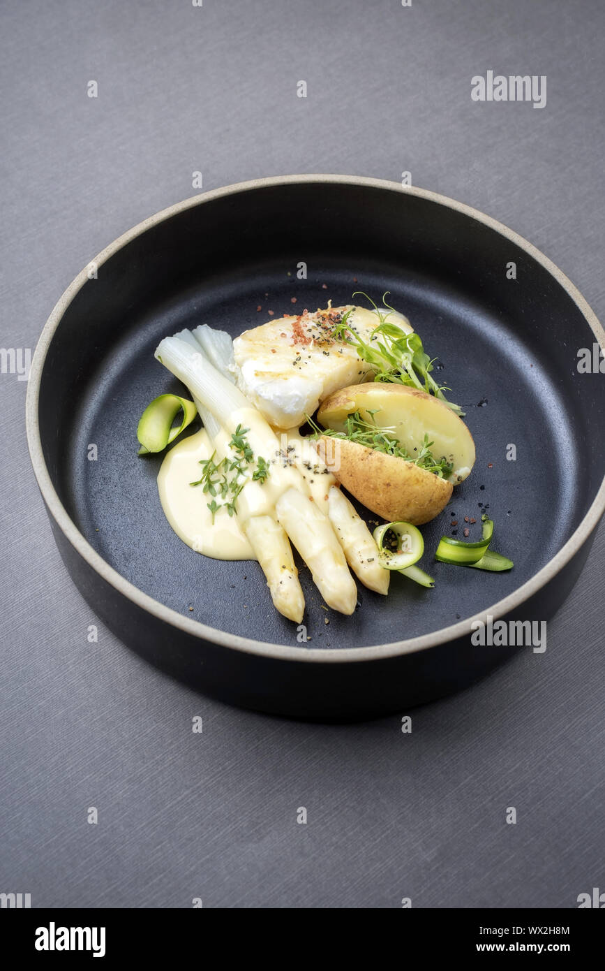 Modern German fried cod fish filet with white asparagus in hollandaise ...