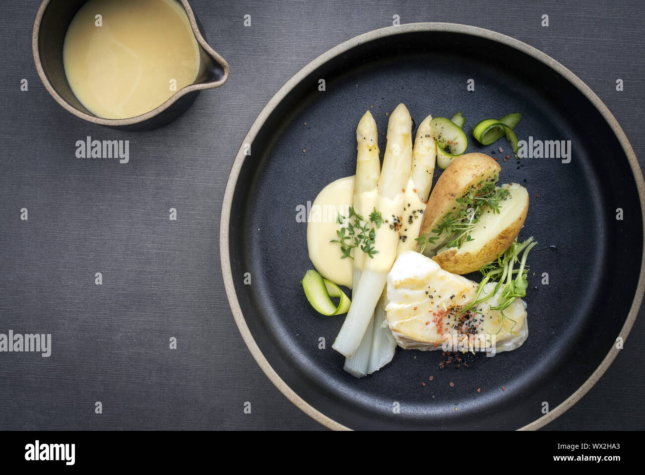 Modern German fried cod fish filet with white asparagus in hollandaise ...