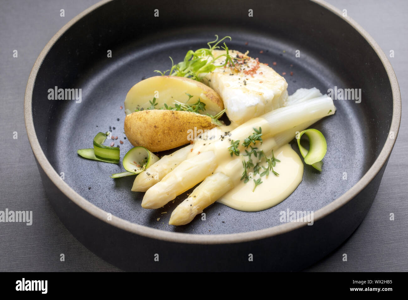 Modern German fried cod fish filet with white asparagus in hollandaise ...