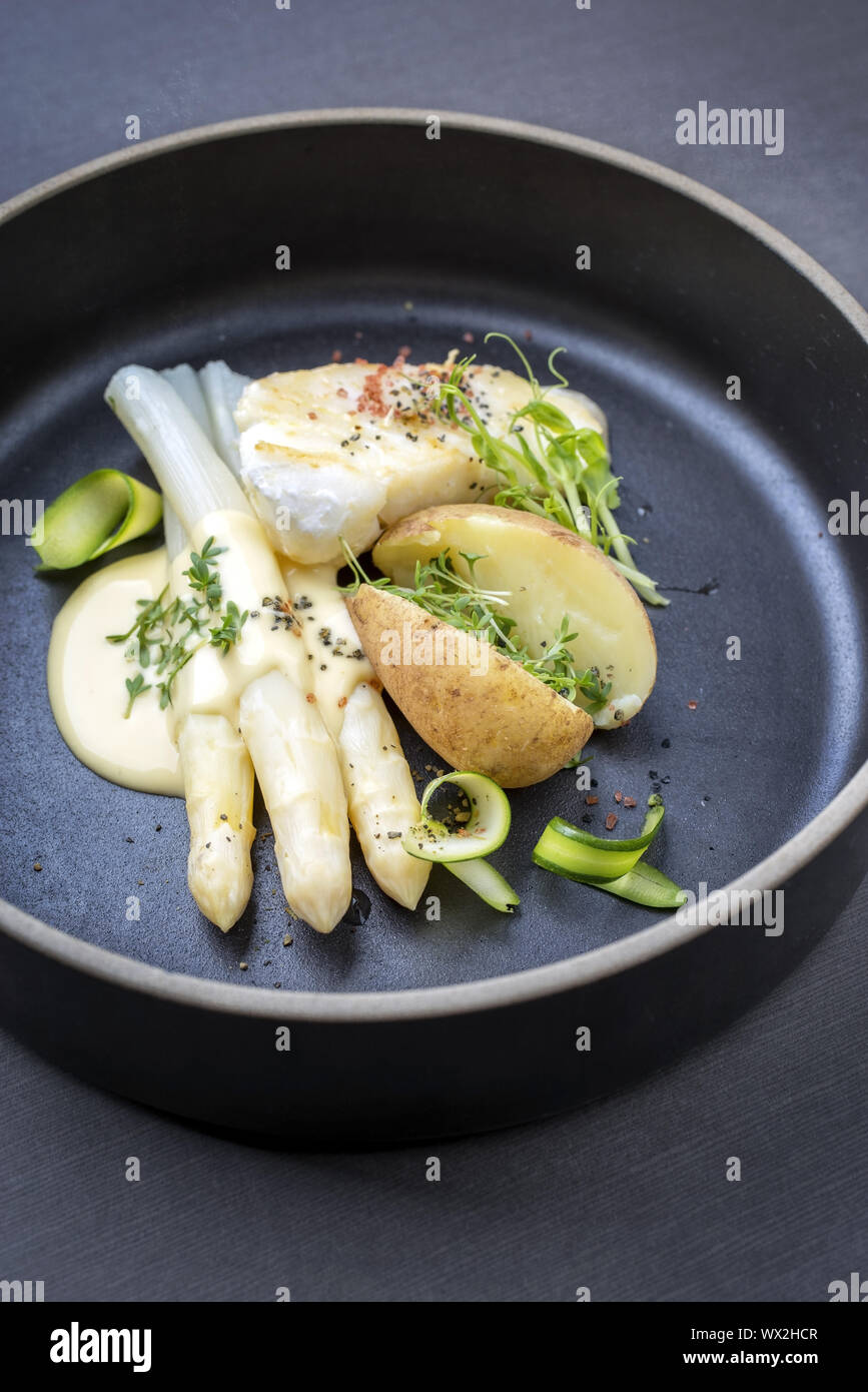 Modern German fried cod fish filet with white asparagus in hollandaise ...