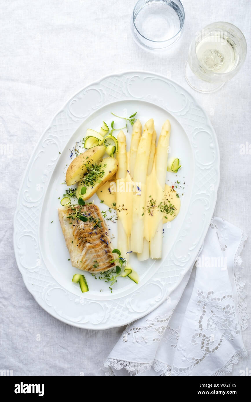 Modern German fried cod fish filet with white asparagus in hollandaise ...