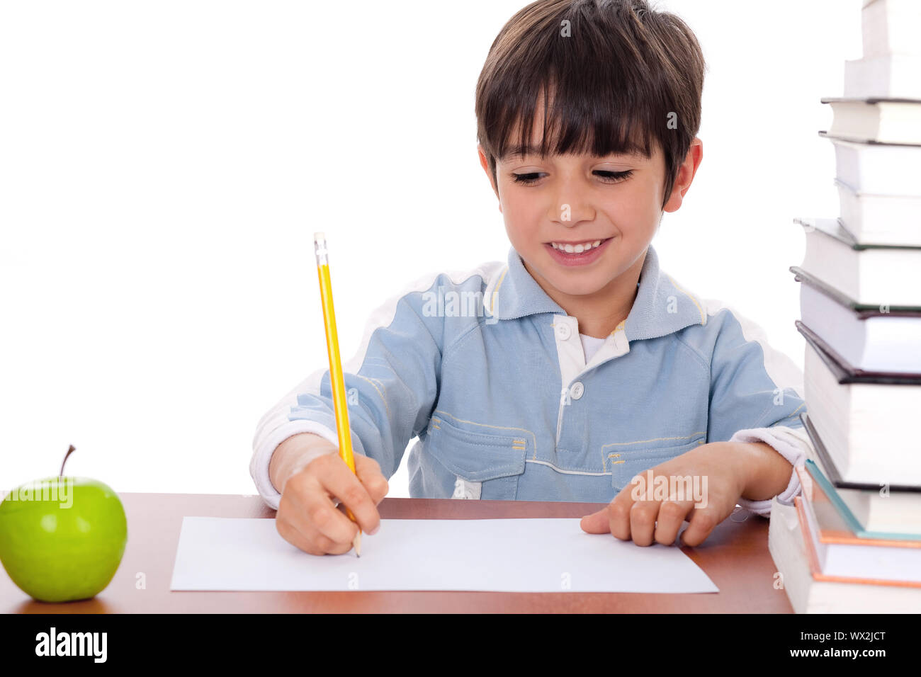 School boy doing his homework with an apple beside him on white ...