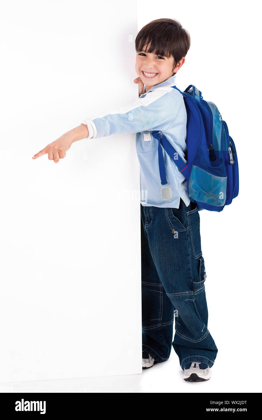 Young kid happily standing behind the board and pointing to empty space ...