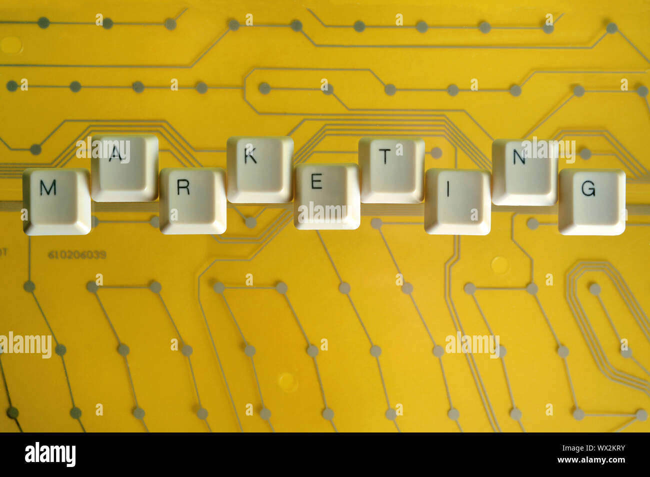 Keyboard keys form the word MARKETING on yellow electric circuit in the ...