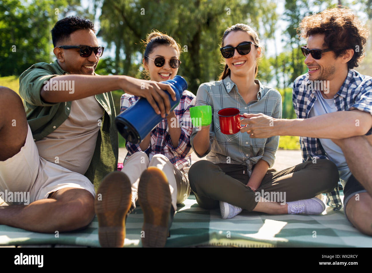 happy friends drinking tea from thermos in summer Stock Photo - Alamy