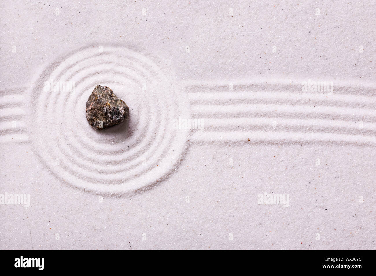 A simple zen rock garden design with a rough stone Stock Photo - Alamy