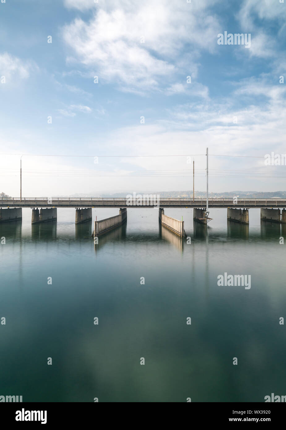vertical view of a concrete bridge over water with a train line and ...
