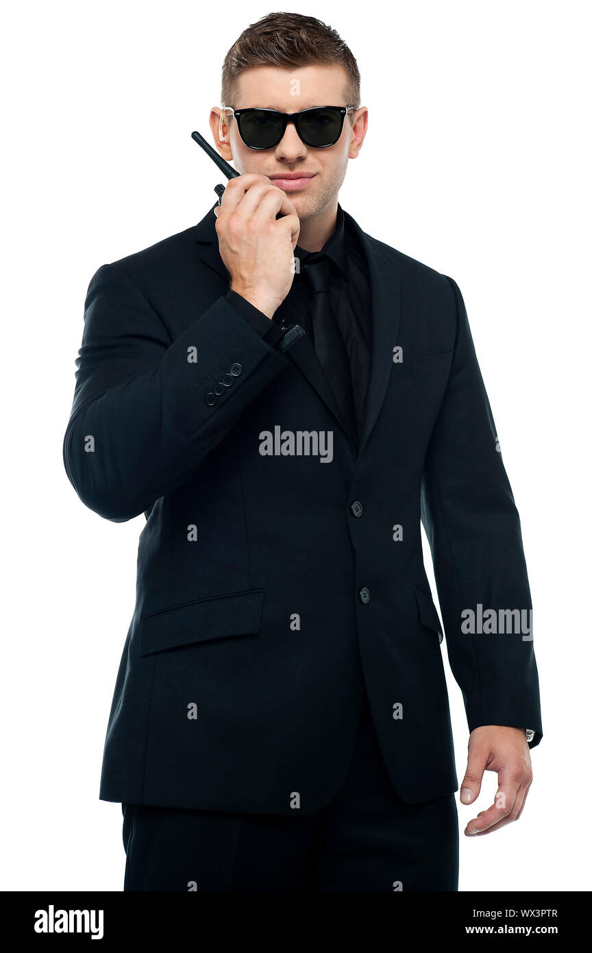 Young sincere security officer talking through his walkie-talkie ...