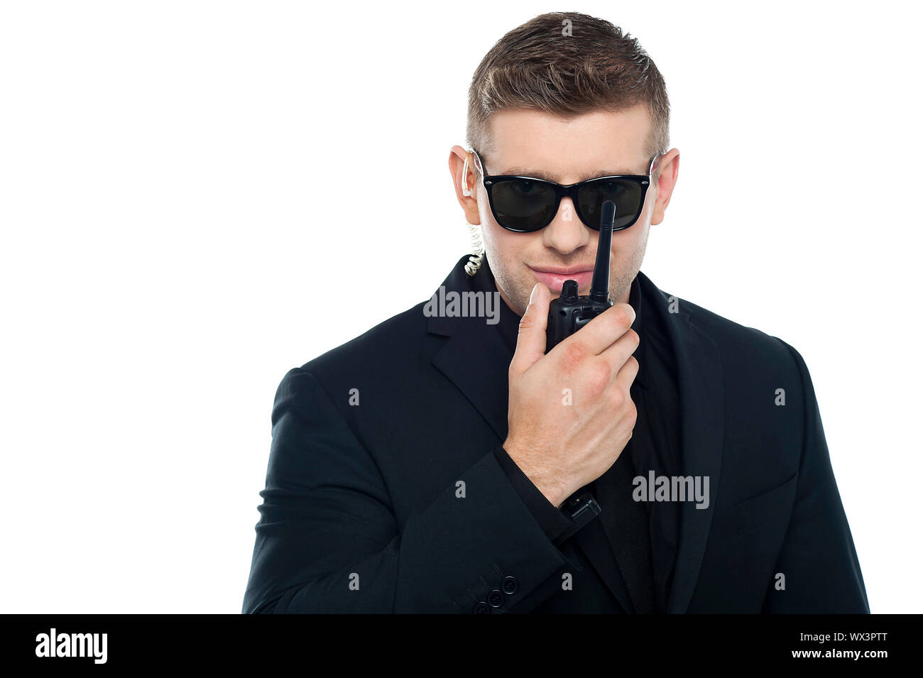 Smart young security personnel communicating over the walkie-talkie ...