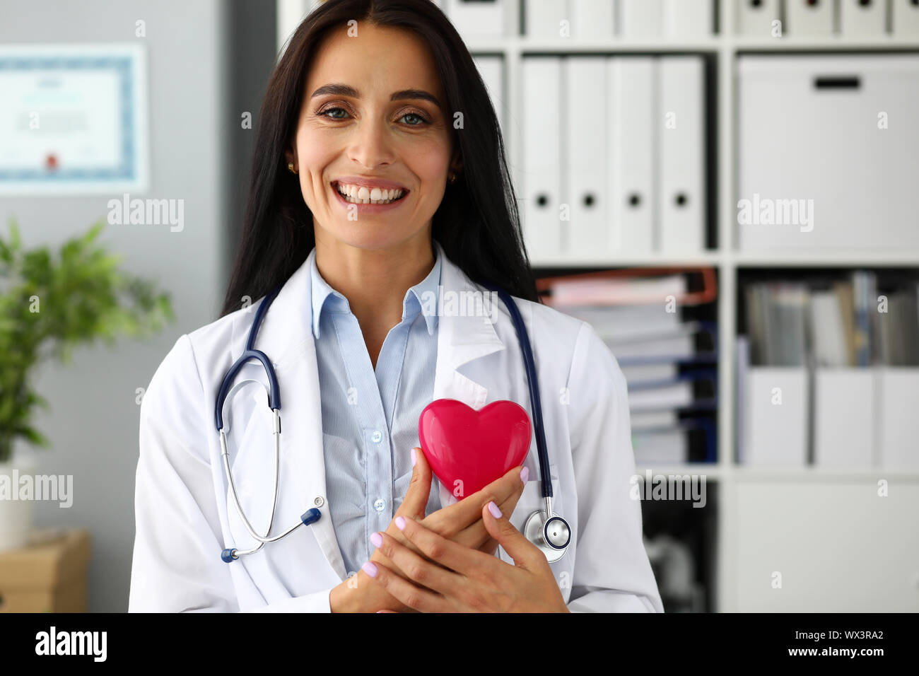 Beautiful smiling GP holding in hands red toy heart Stock Photo - Alamy
