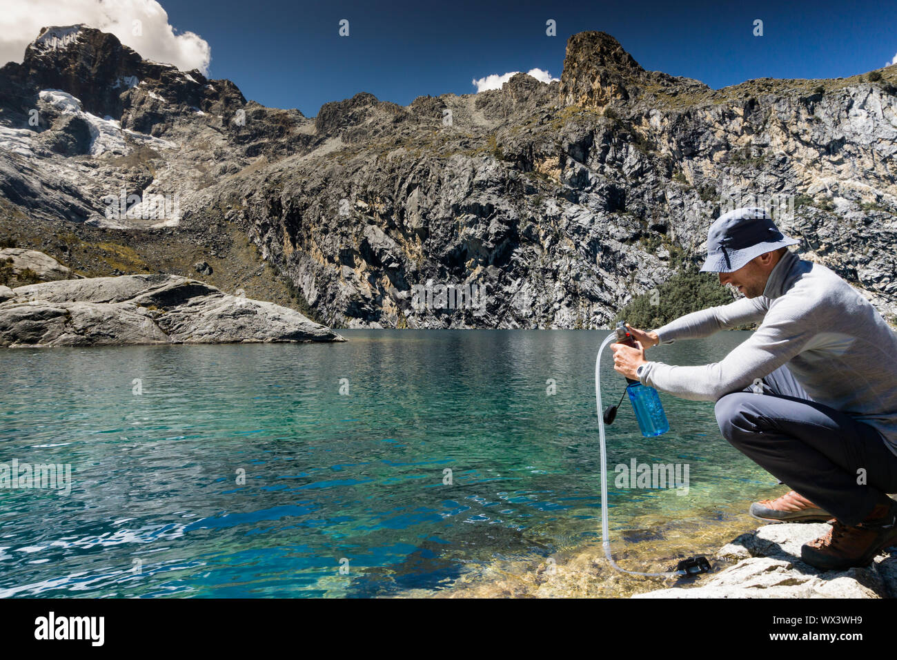 mountain climber pumping and filtering drinking water from a lake in ...