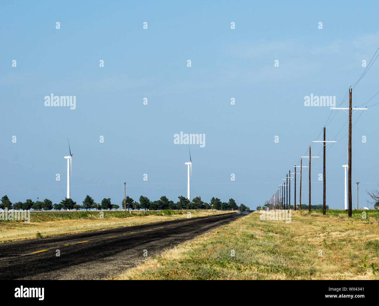 country road in the empty Texas prairie with power lines and wind ...
