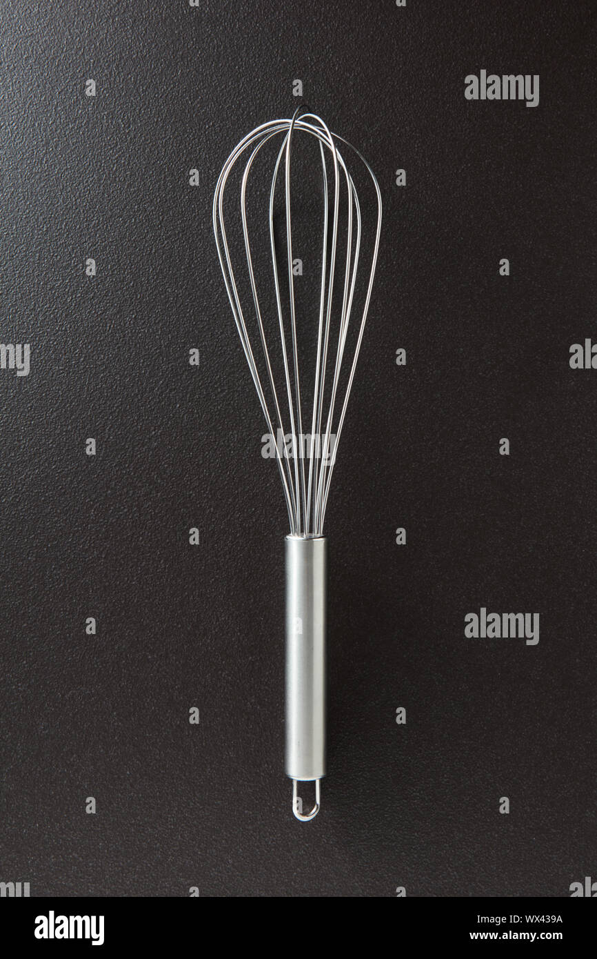 Kitchen metal beater on a black concrete background with copy space ...
