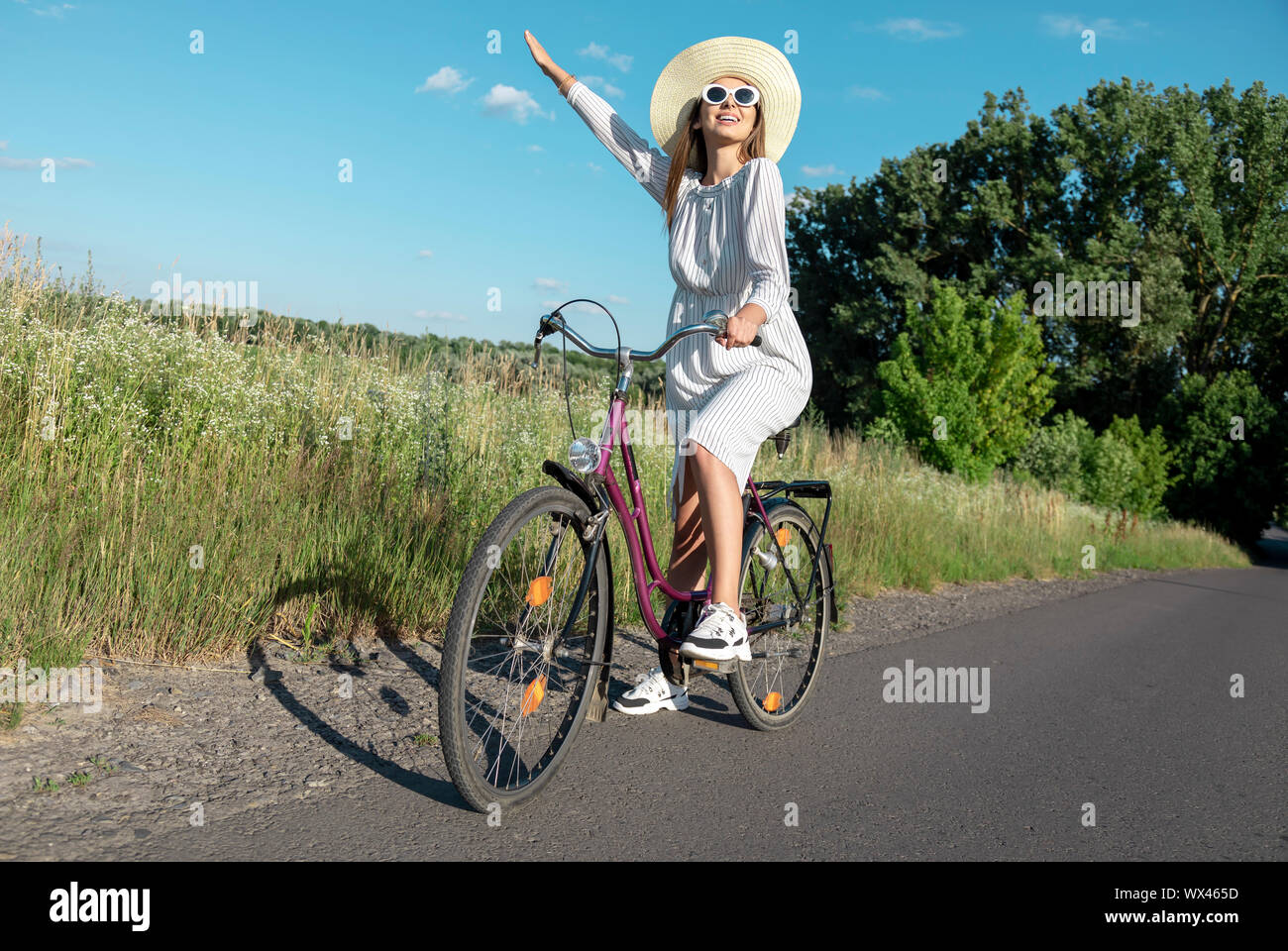 Young charming cyclist women feeling fresh wind by her hand while ...