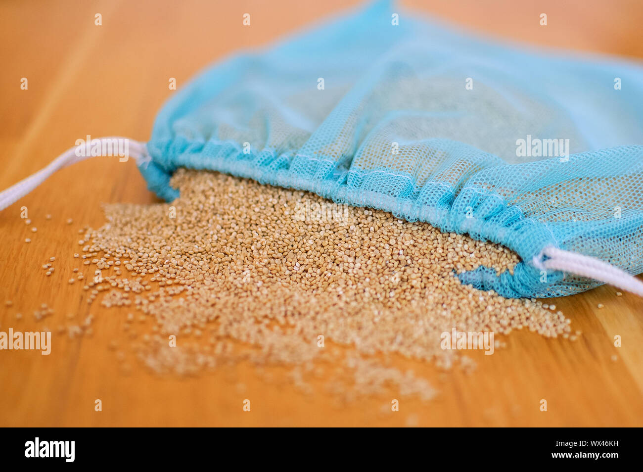 Close up of white quinoa seeds in blue reusable package on wooden ...