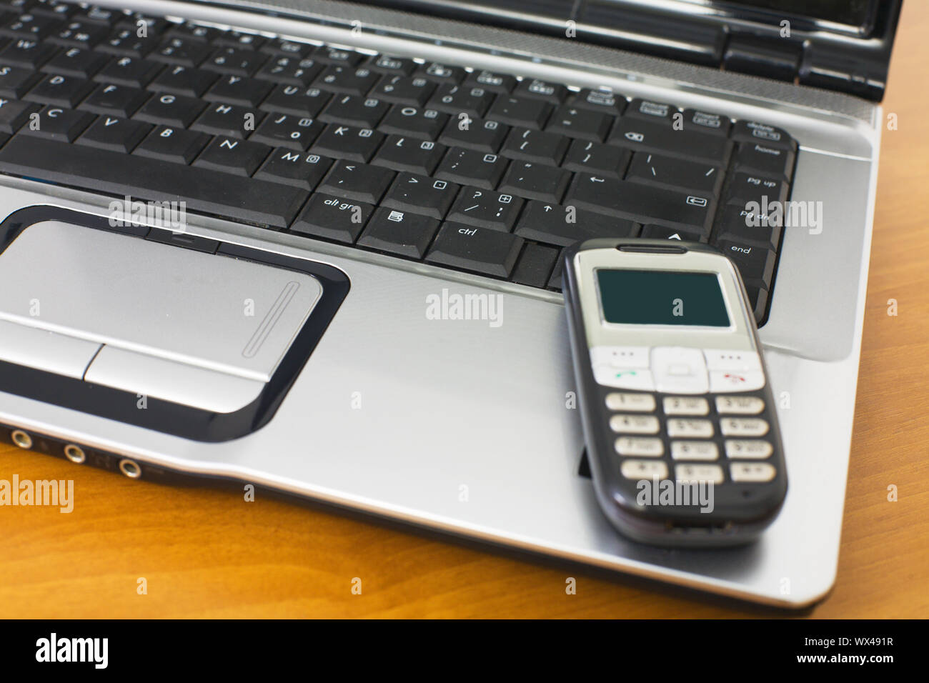 Mobile telephone lying on keyboard on the wooden table Stock Photo - Alamy