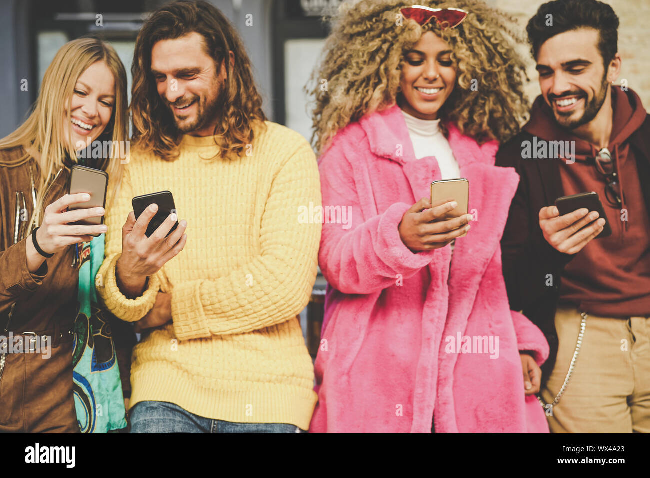 Group of friends watching on their mobile phones outdoor - Millennial ...
