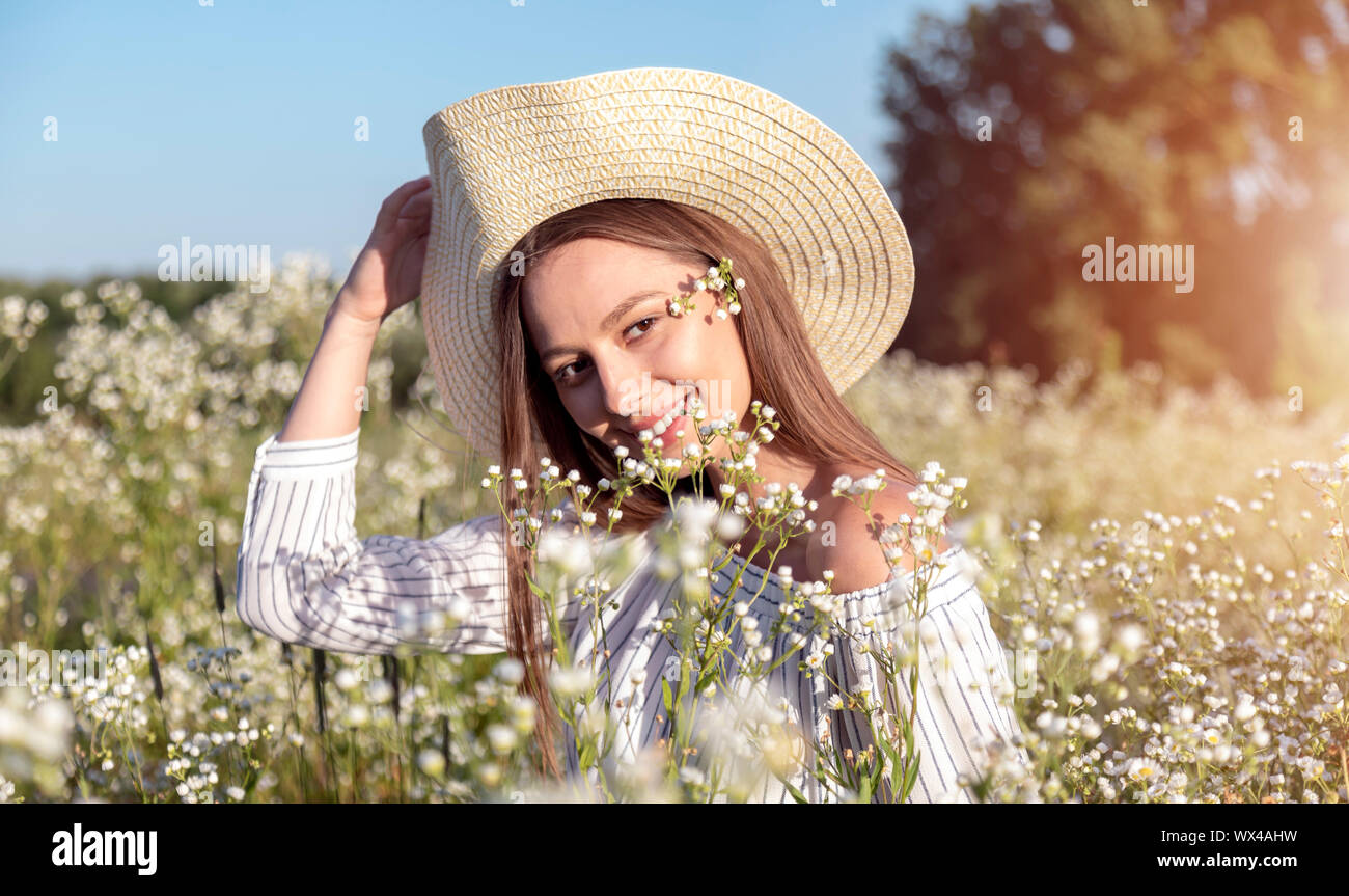 Cute tourist girl in straw hat posing amidst flowery field Stock Photo ...