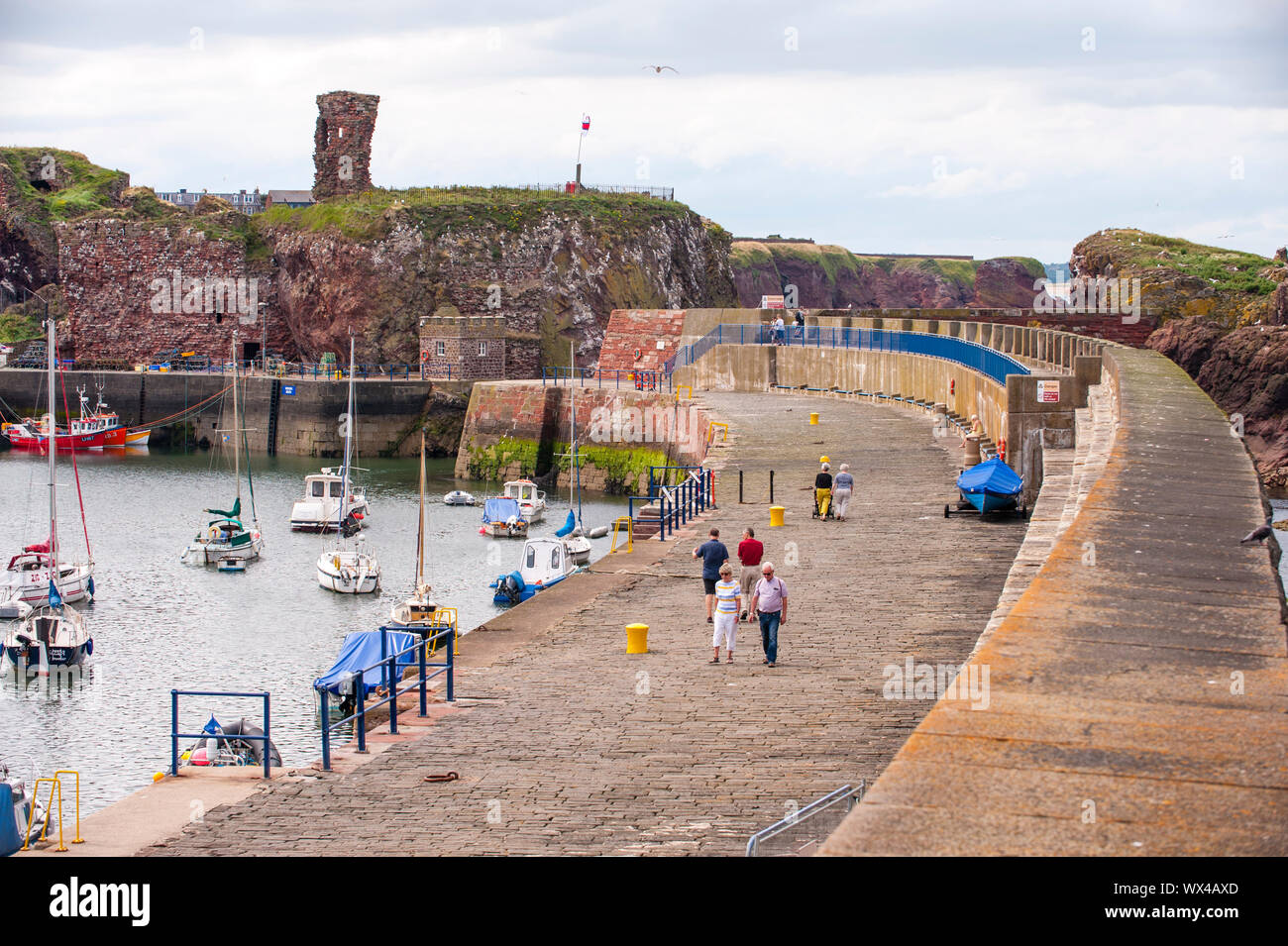 Boats and houses in Dunbar harbour during low tide. Dunbar is a town ...