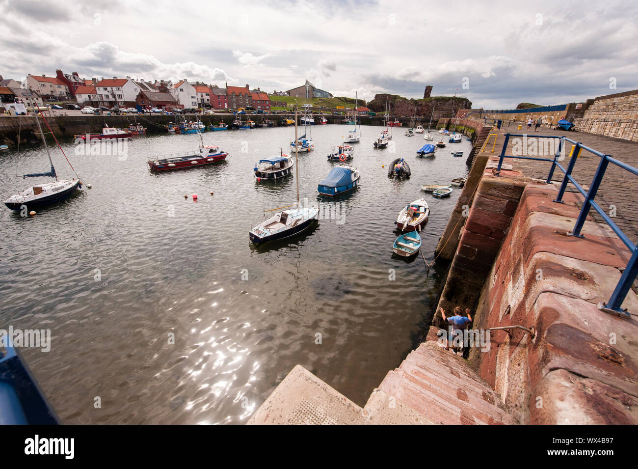 Boats and houses in Dunbar harbour during low tide. Dunbar is a town ...