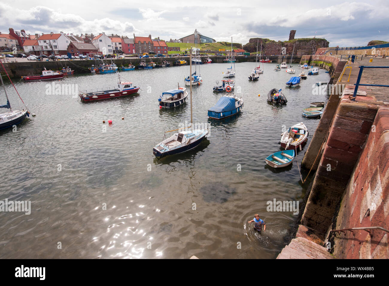 Boats and houses in Dunbar harbour during low tide. Dunbar is a town ...