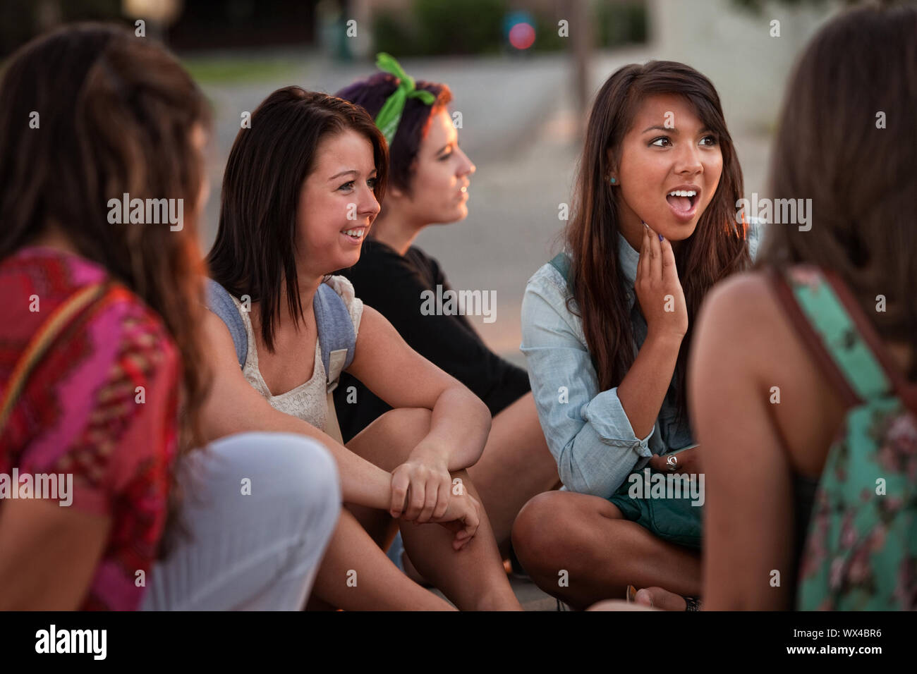 Disgusted teenage girl sitting on the ground talking with friends Stock ...