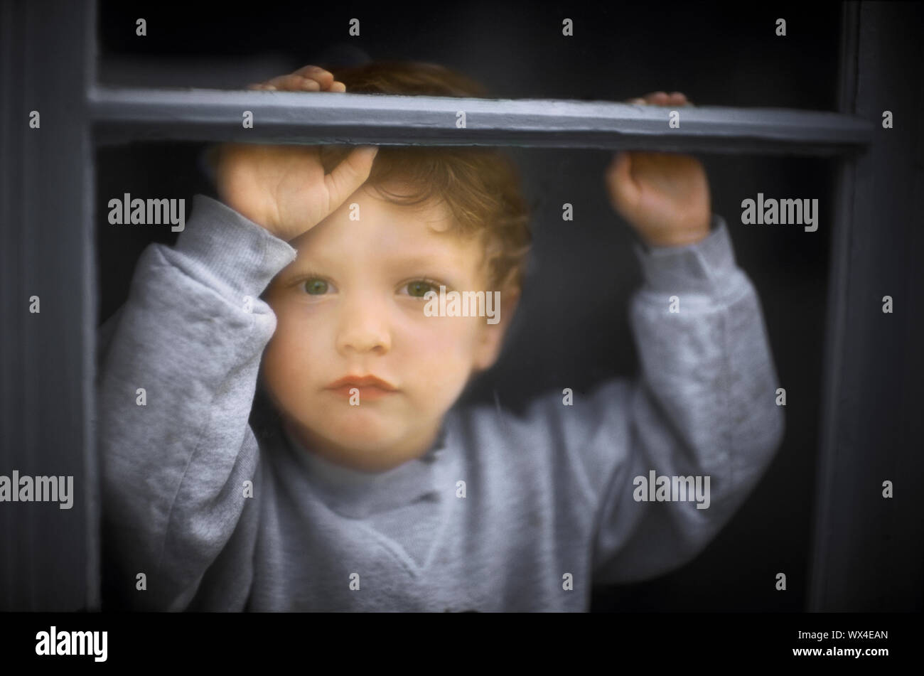 Portrait of a young child looking out of a window Stock Photo - Alamy
