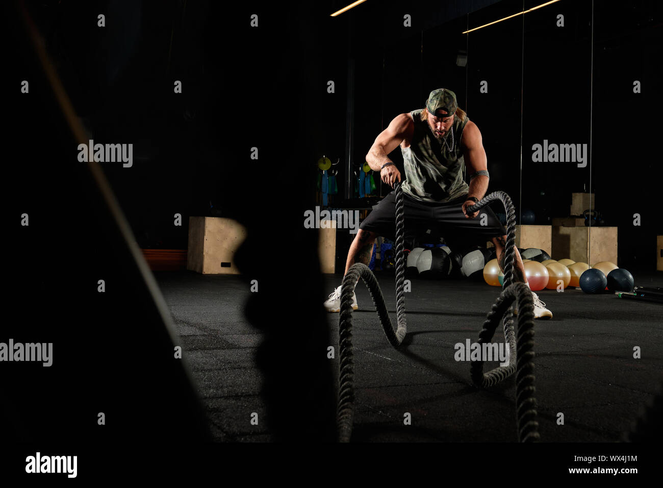Muscular man in a sports uniform and a baseball cap performs an ...