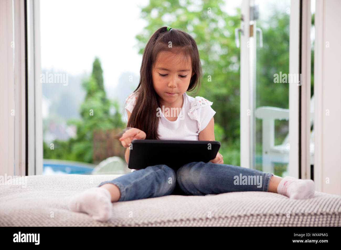Cute young child using a digital tablet in a home interior with large ...