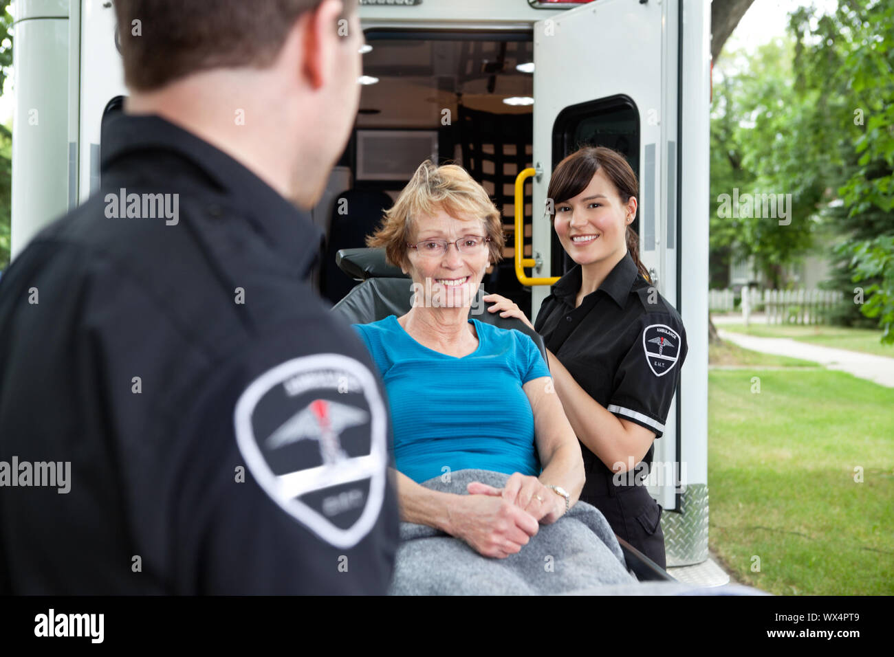 Two ambulance workers pushing a happy femaile patient Stock Photo - Alamy