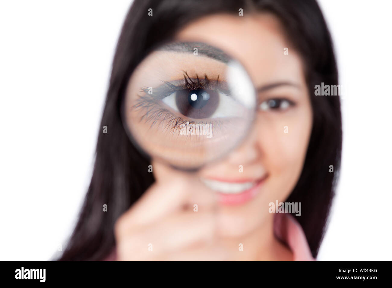 Happy young woman looking through magnifying glass isolated on white ...