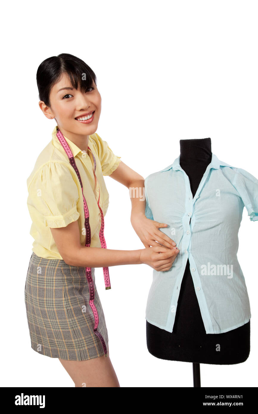 Young Asian woman dressmaker adjusting clothes on tailoring mannequin ...