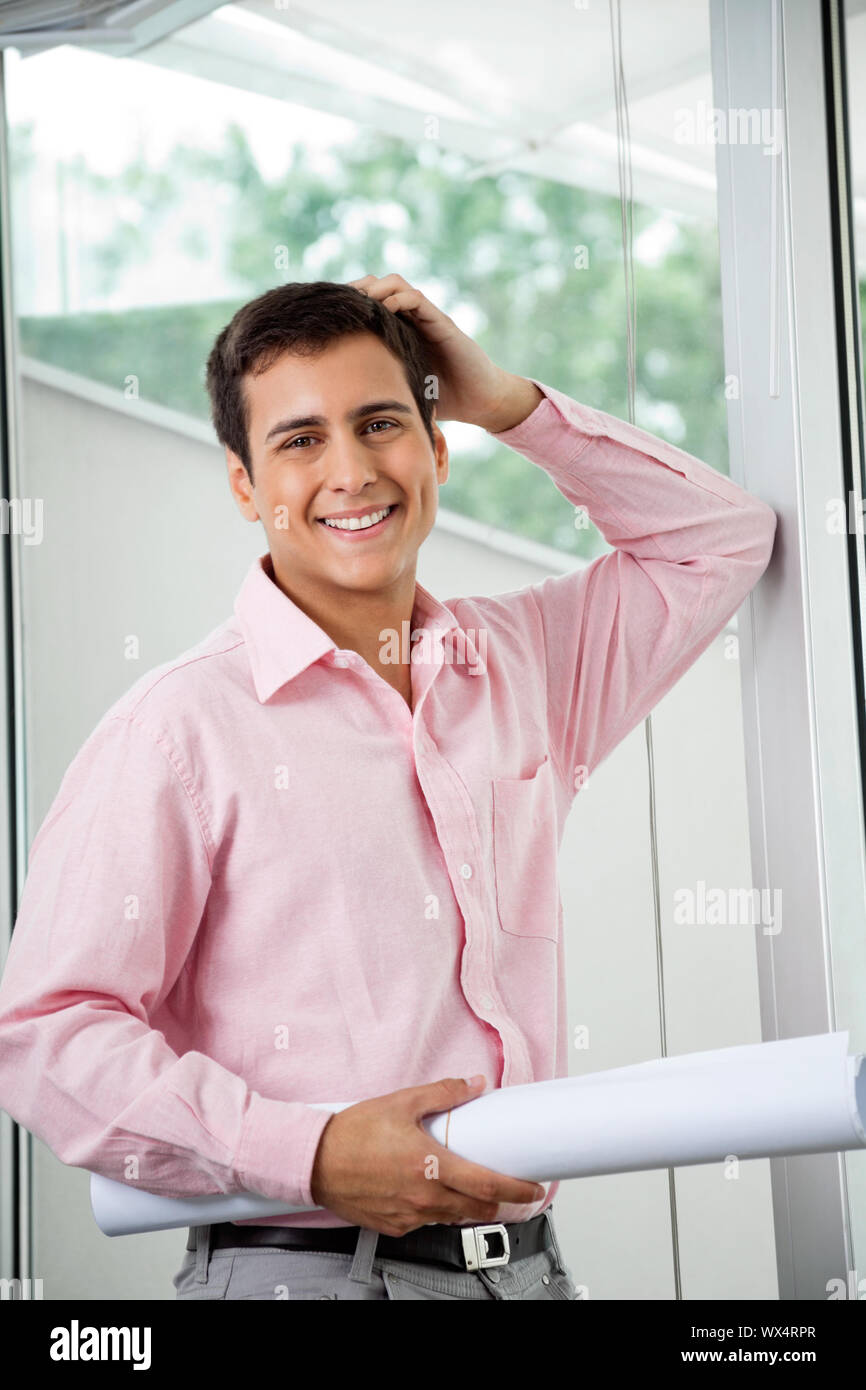 Portrait of young male architect smiling while holding a rolled up ... Portrait of young male architect smiling while holding a rolled up ...