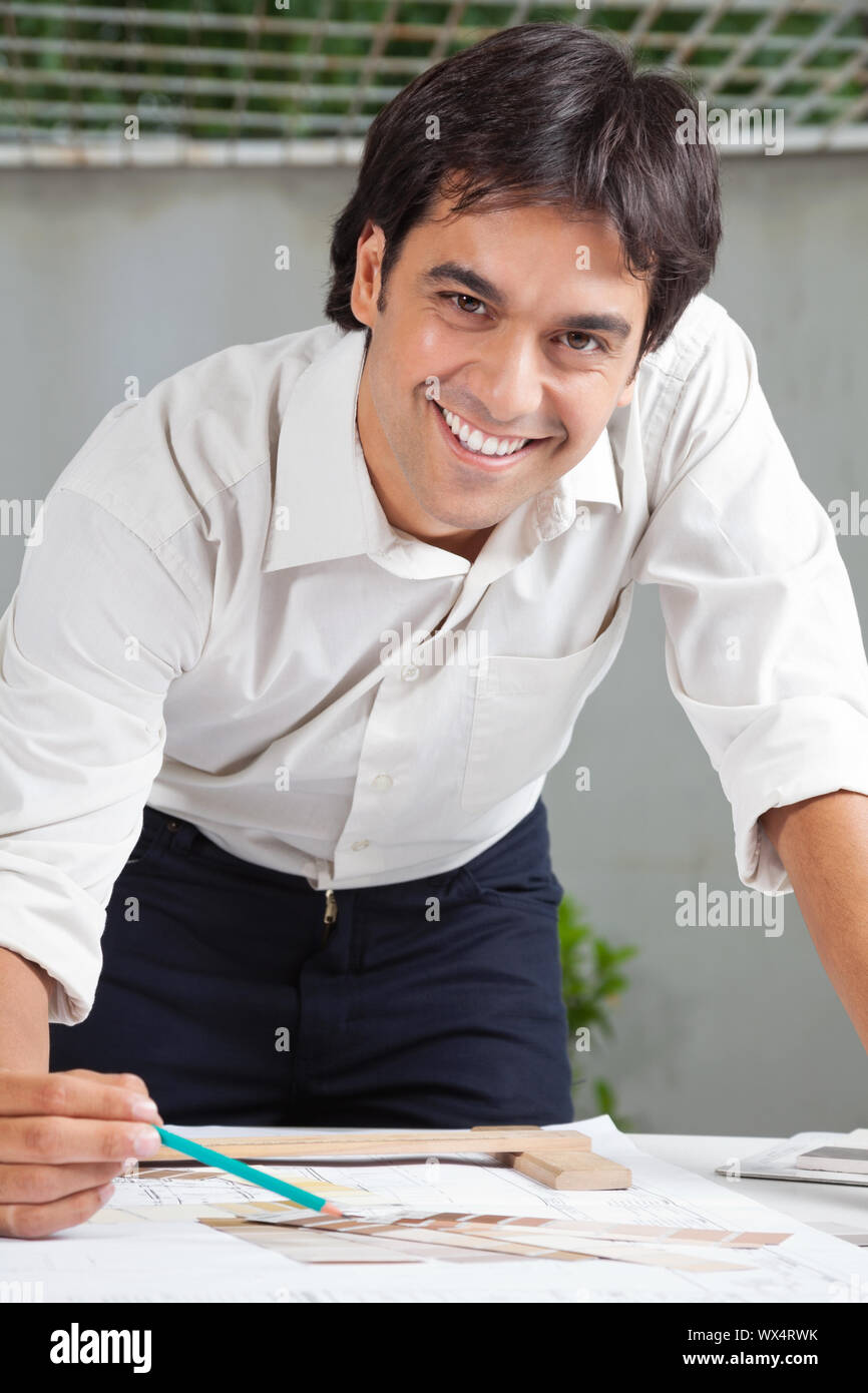 Portrait of young male architect smiling while working on blueprint ... Portrait of young male architect smiling while working on blueprint ...